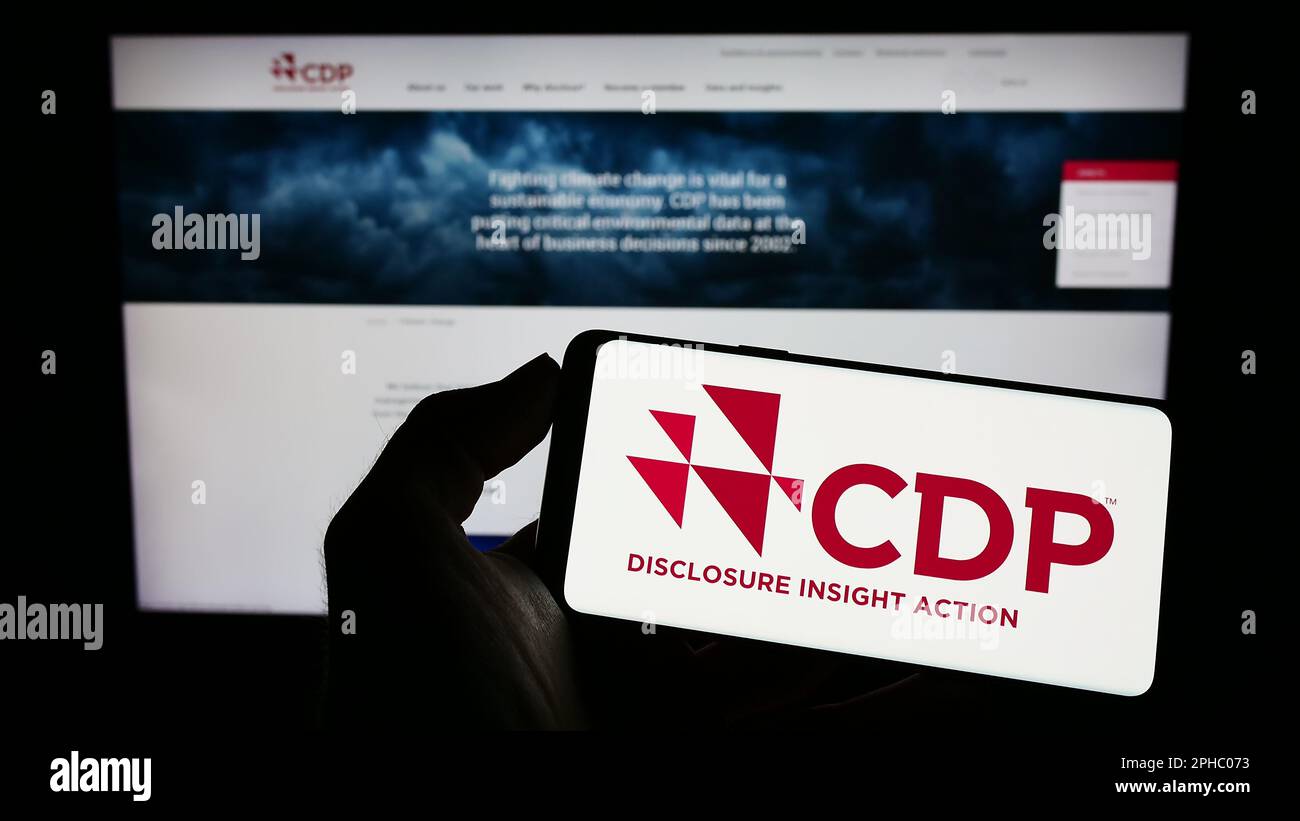 Person holding mobile phone with logo of organization Carbon Disclosure ...