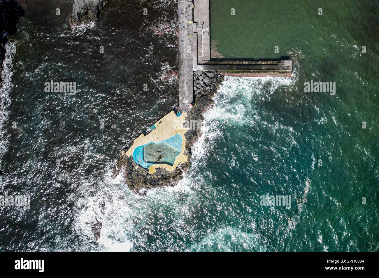Drone view of the Caloura natural swimming pool, located in a seaside ...