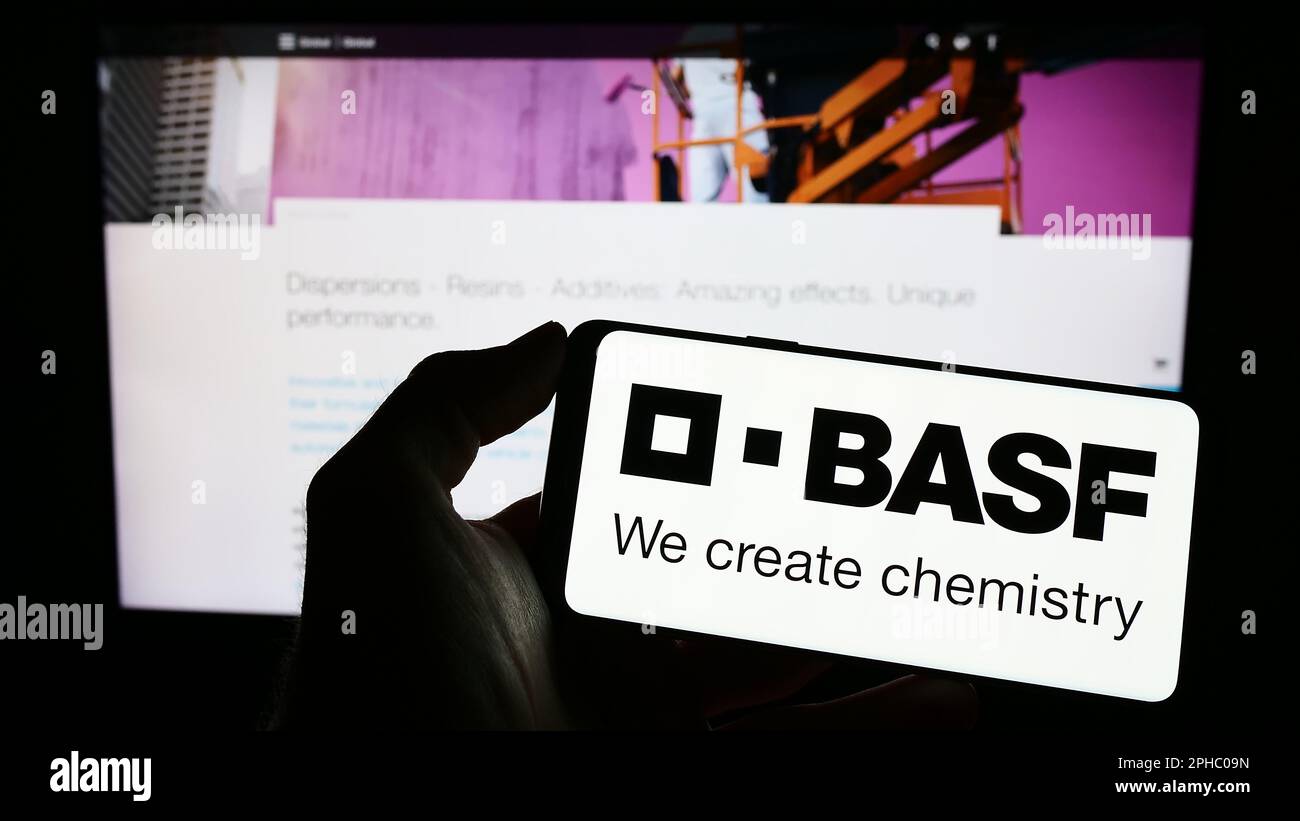 Person holding smartphone with logo of German chemical company BASF SE ...