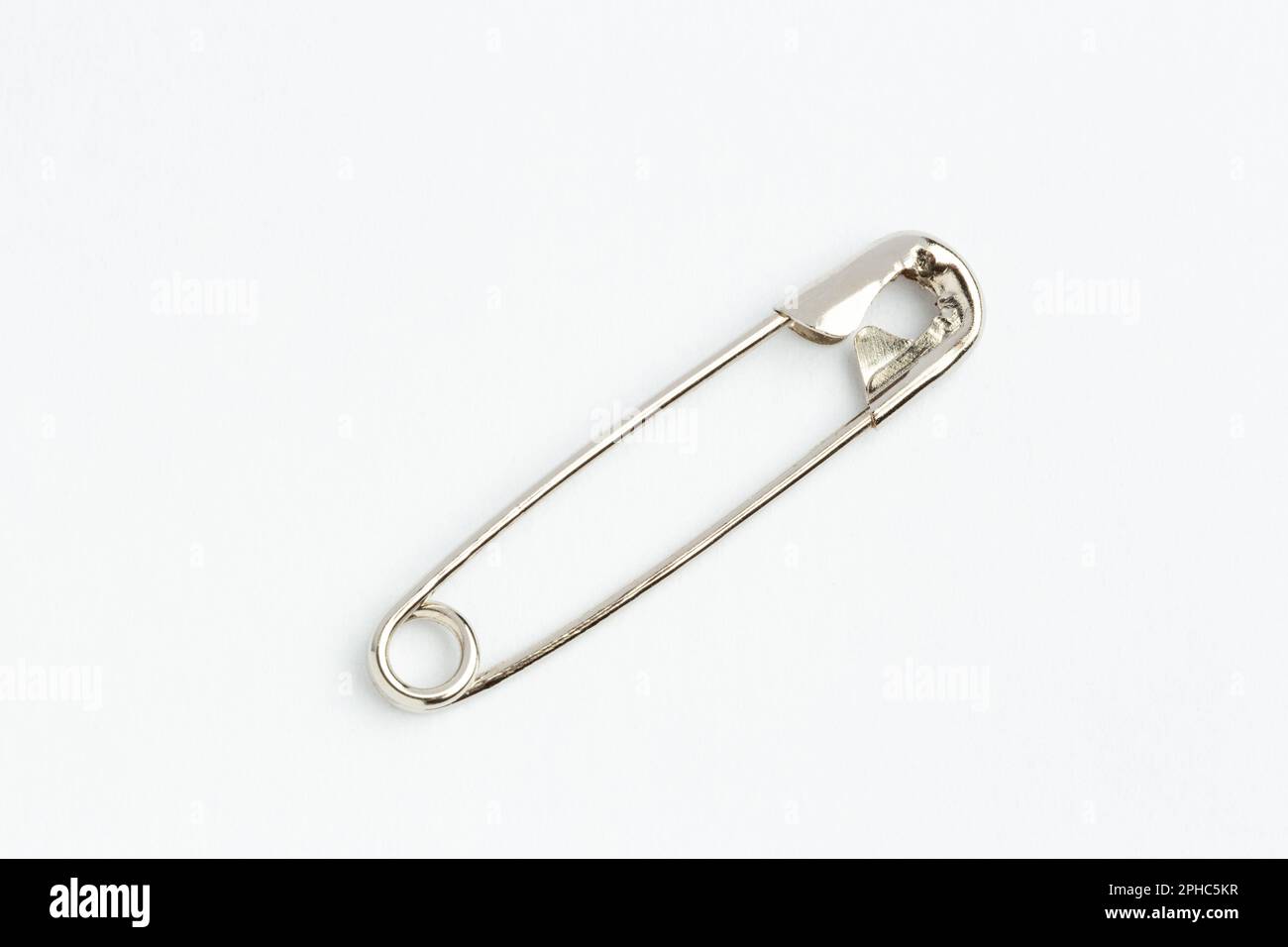 Safety pin on white background Stock Photo - Alamy