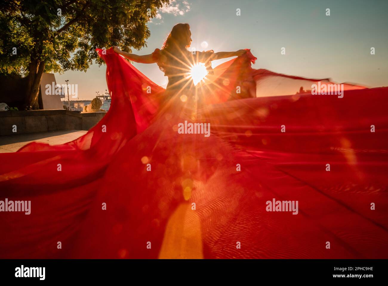 Sunrise red dress. A woman in a long red dress against the backdrop of ...