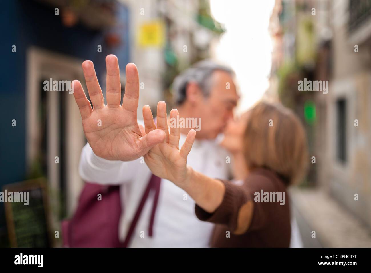 Senior Couple Kissing Covering Camera With Hands Standing Outside Stock ...