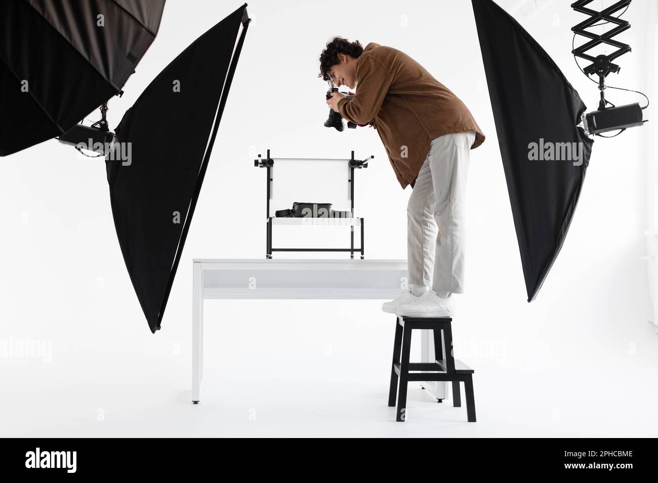 Professional male photographer standing on ladder and taking high angle ...