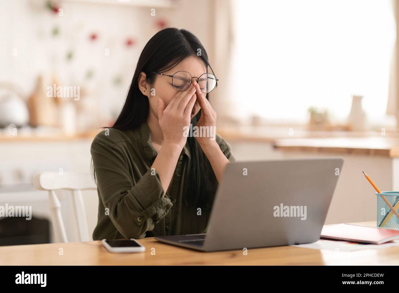 Tired korean woman digital nomad rubbing eyes, using laptop Stock Photo ...