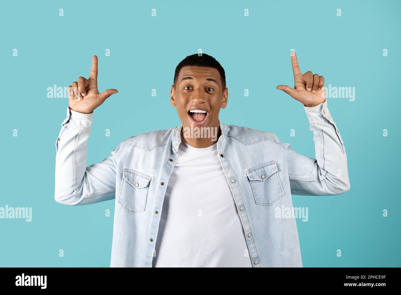 Glad happy millennial black male pointing finger up at empty space ...