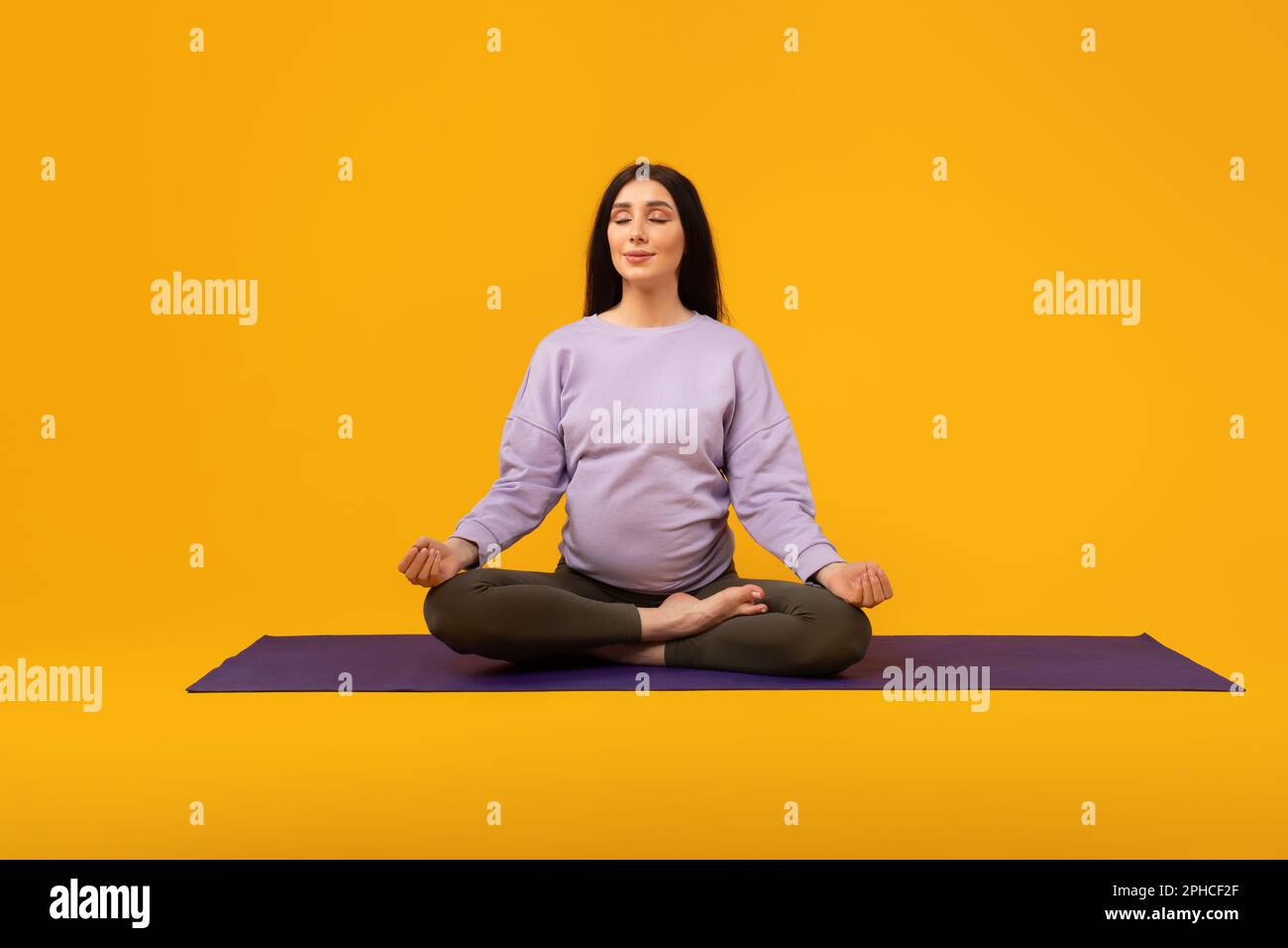 Portrait of positive pregnant woman meditating on yoga mat, expecting ...