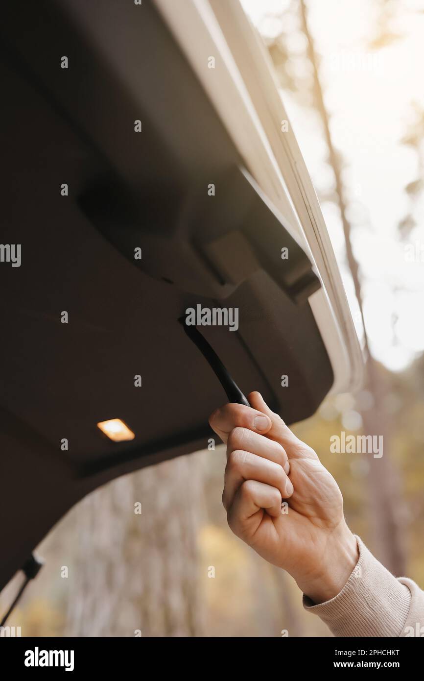 Unrecognisable man holds trunk handle and closes car trunk door ...