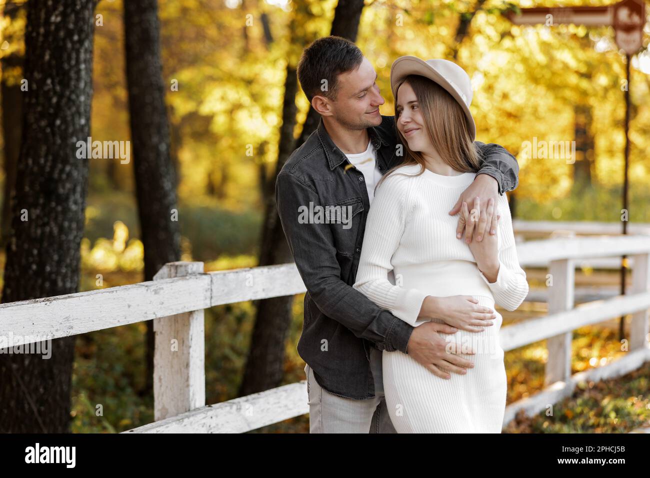 Happy stylish pregnant woman and man hugs, kiss, touches belly and ...