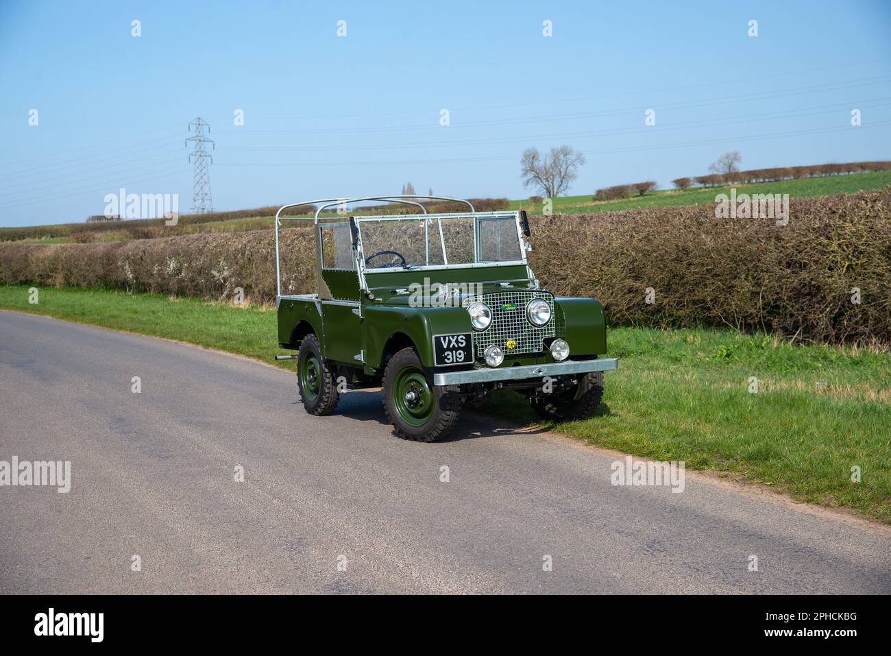 Land Rover Series One parked by the side of a country lane with a hedge ...
