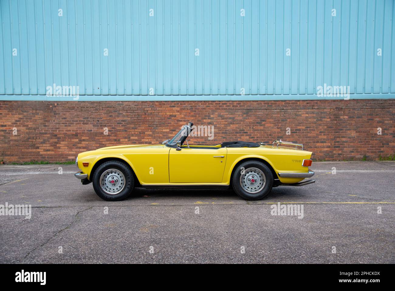 Yellow Triumph TR6 parked on concrete next to a brick wall Stock Photo ...