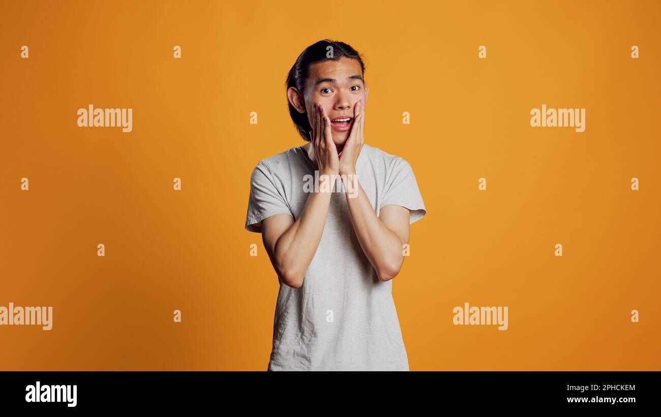 Shocked amazed person covering open mouth, acting stupefied over orange ...