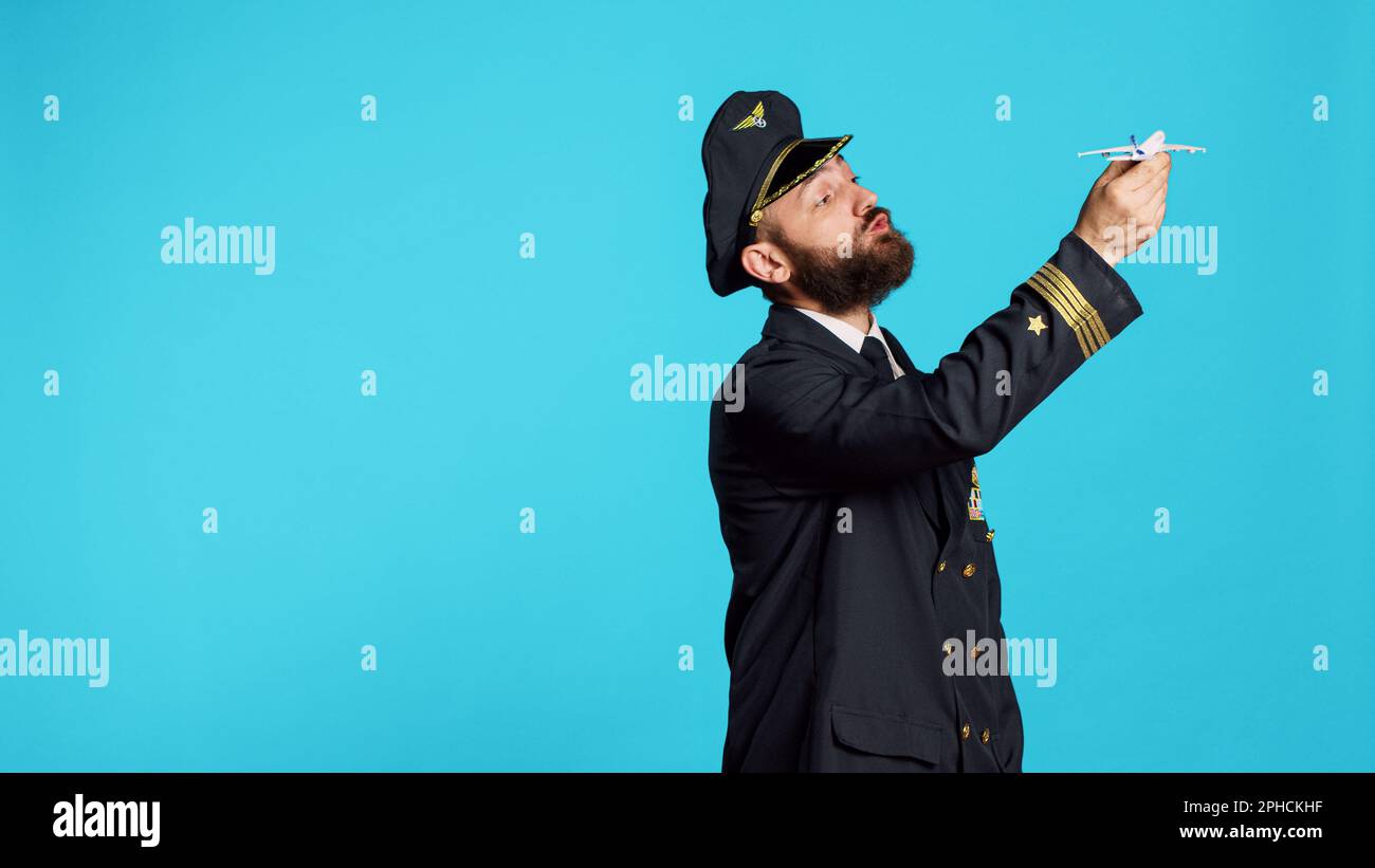 Caucasian man dressed as pilot playing with airplane toy, showing ...