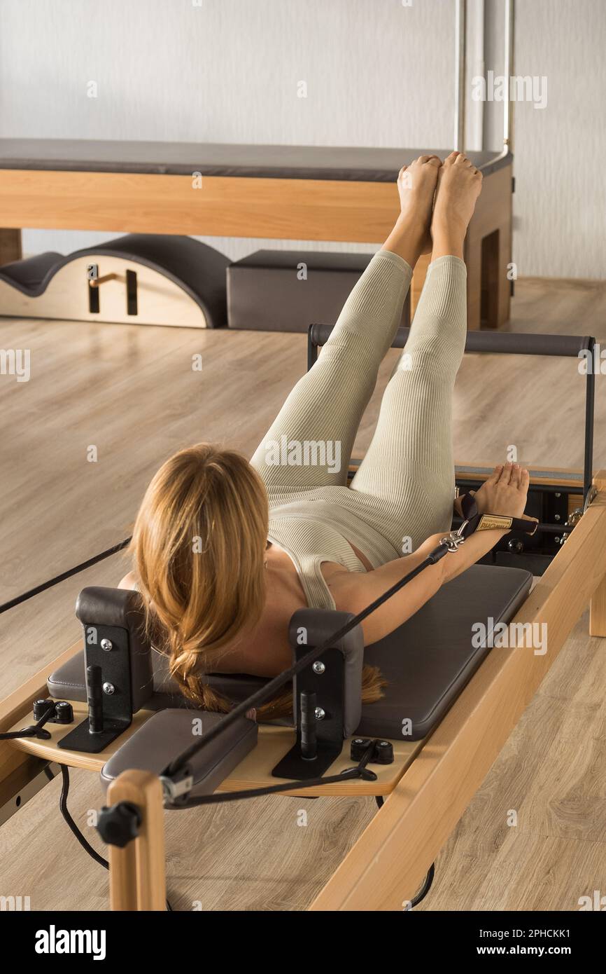 Woman training pilates on the reformer bed. Reformer pilates studio ...