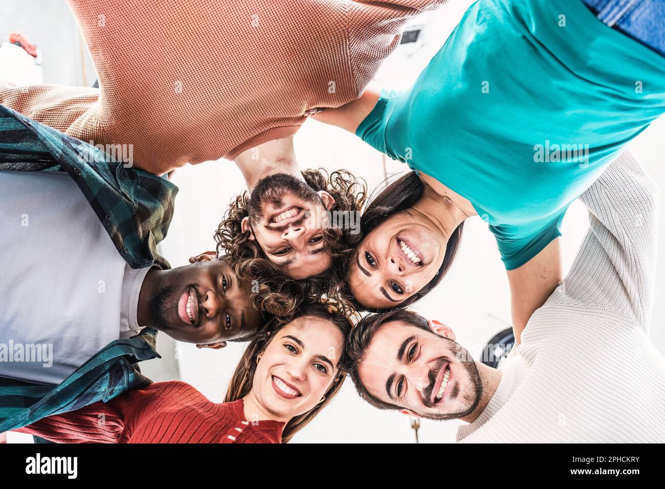 Young happy multi ethnic friends standing in the circle and looking ...