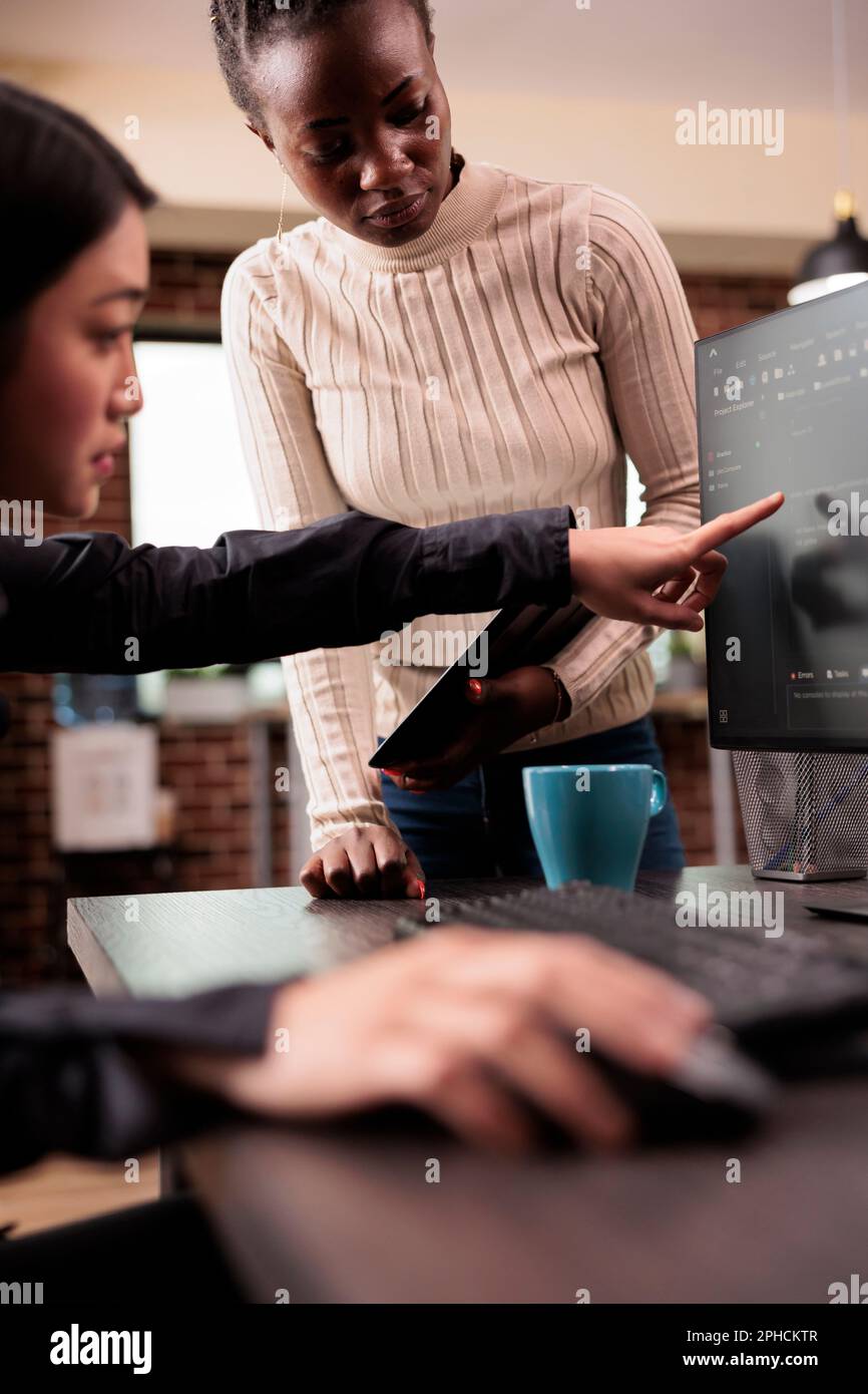 Team of software developers talking about source code running on computer, working with cloud ...