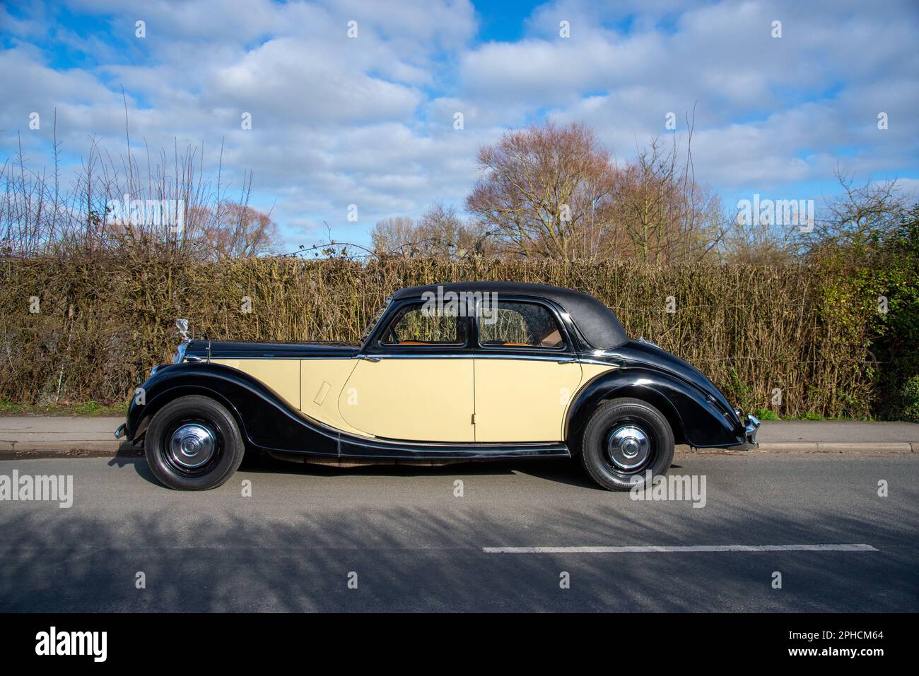 Post war Riley RMB saloon parked on a country road in front of a tall ...