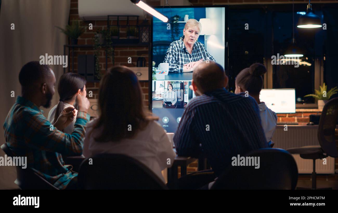 Employees greeting mid adult coworker in videocall, waving hi ...