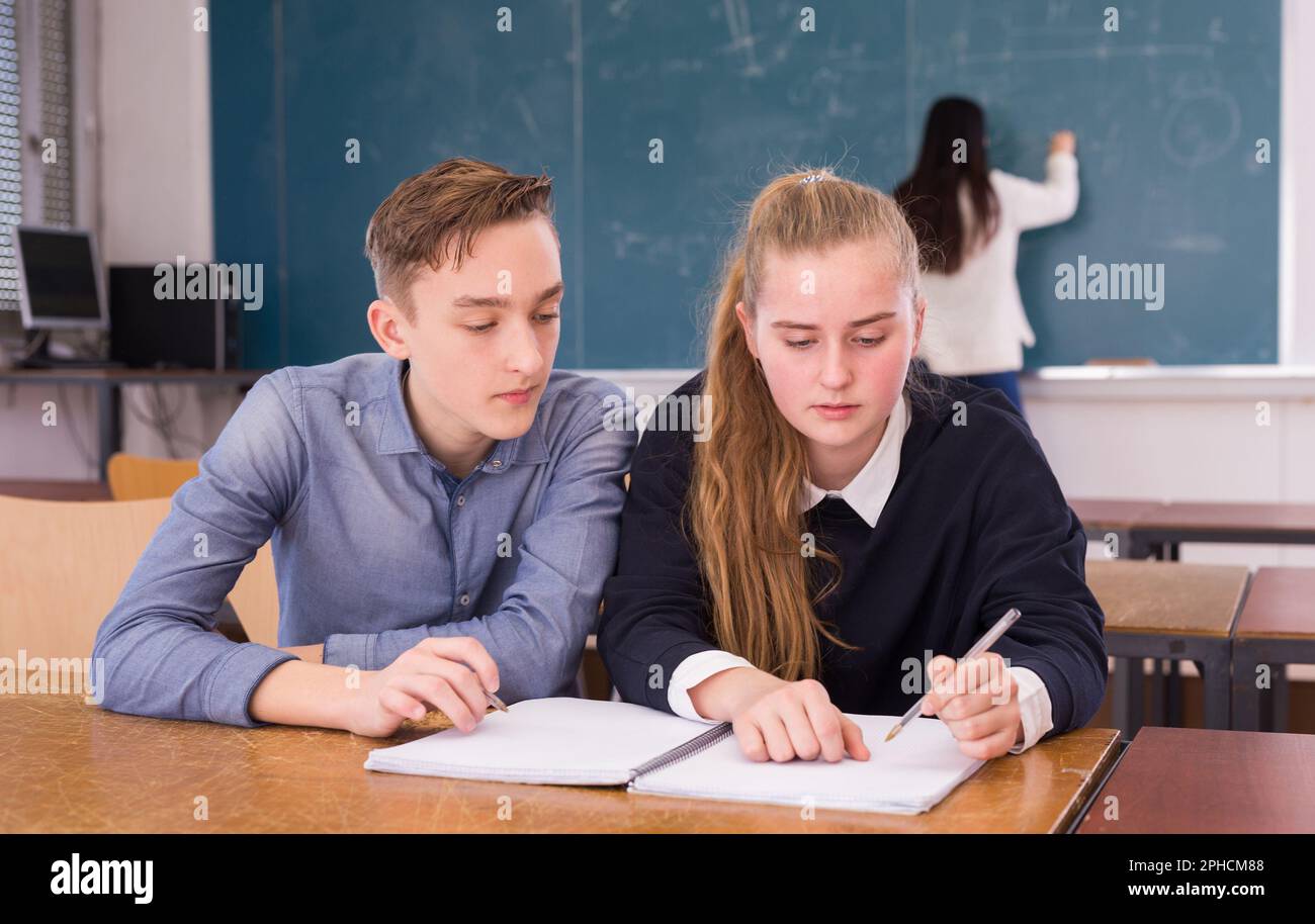 Young guy and girl students doing lesson in classroom Stock Photo - Alamy