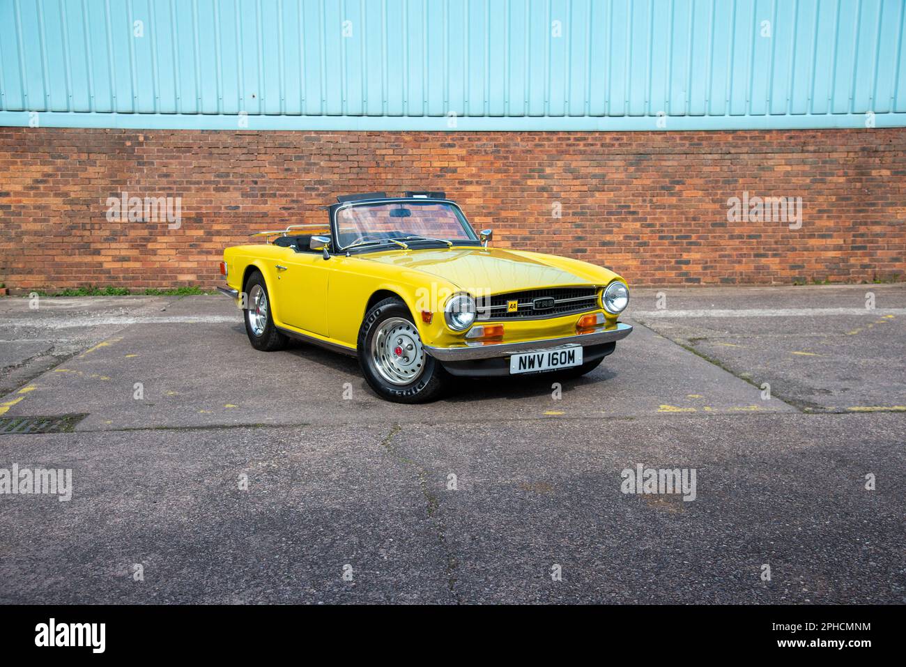Yellow Triumph TR6 parked on concrete next to a brick wall Stock Photo ...