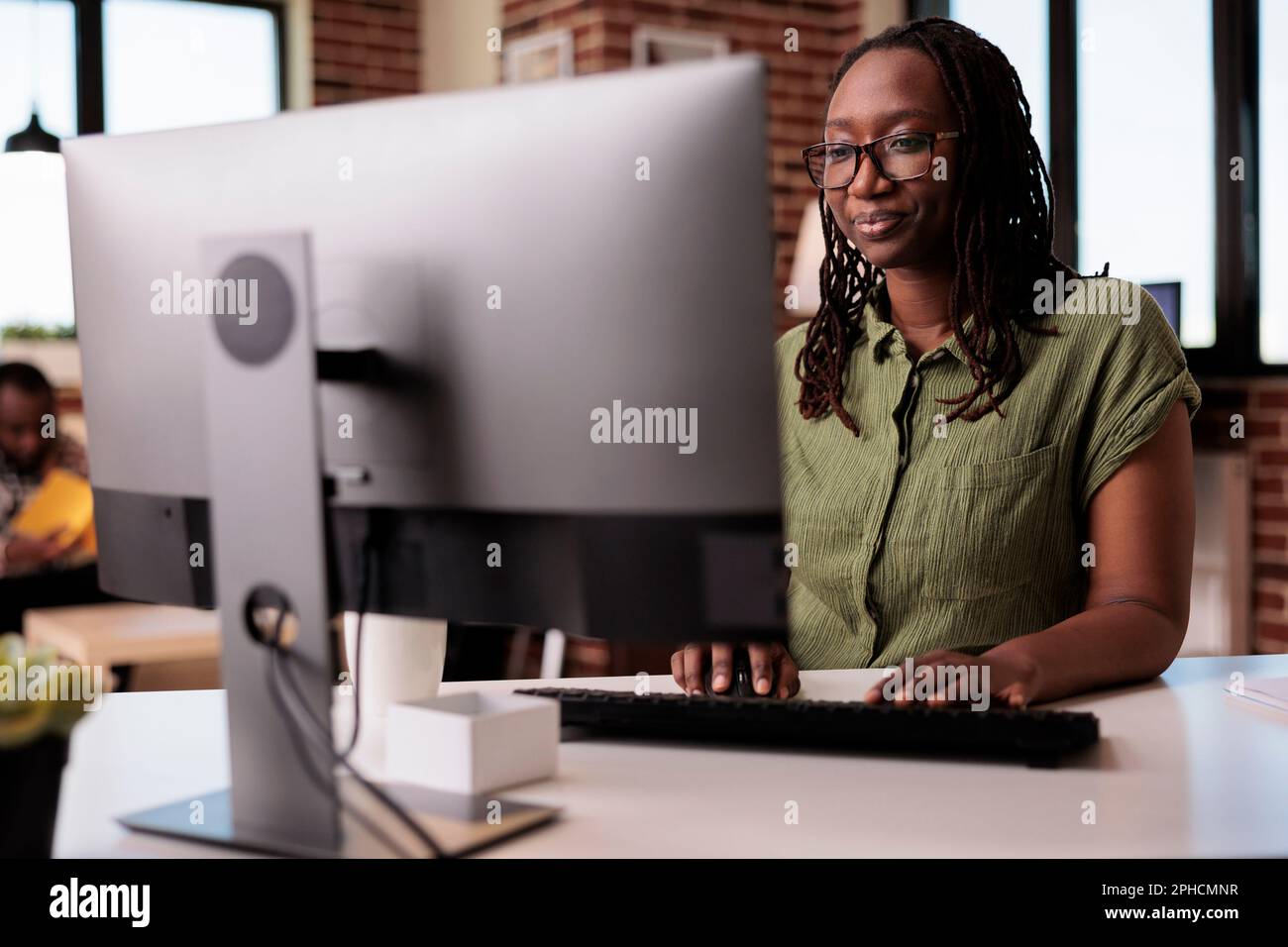 Confident african american freelancer looking at computer screen and typing while working remote ...