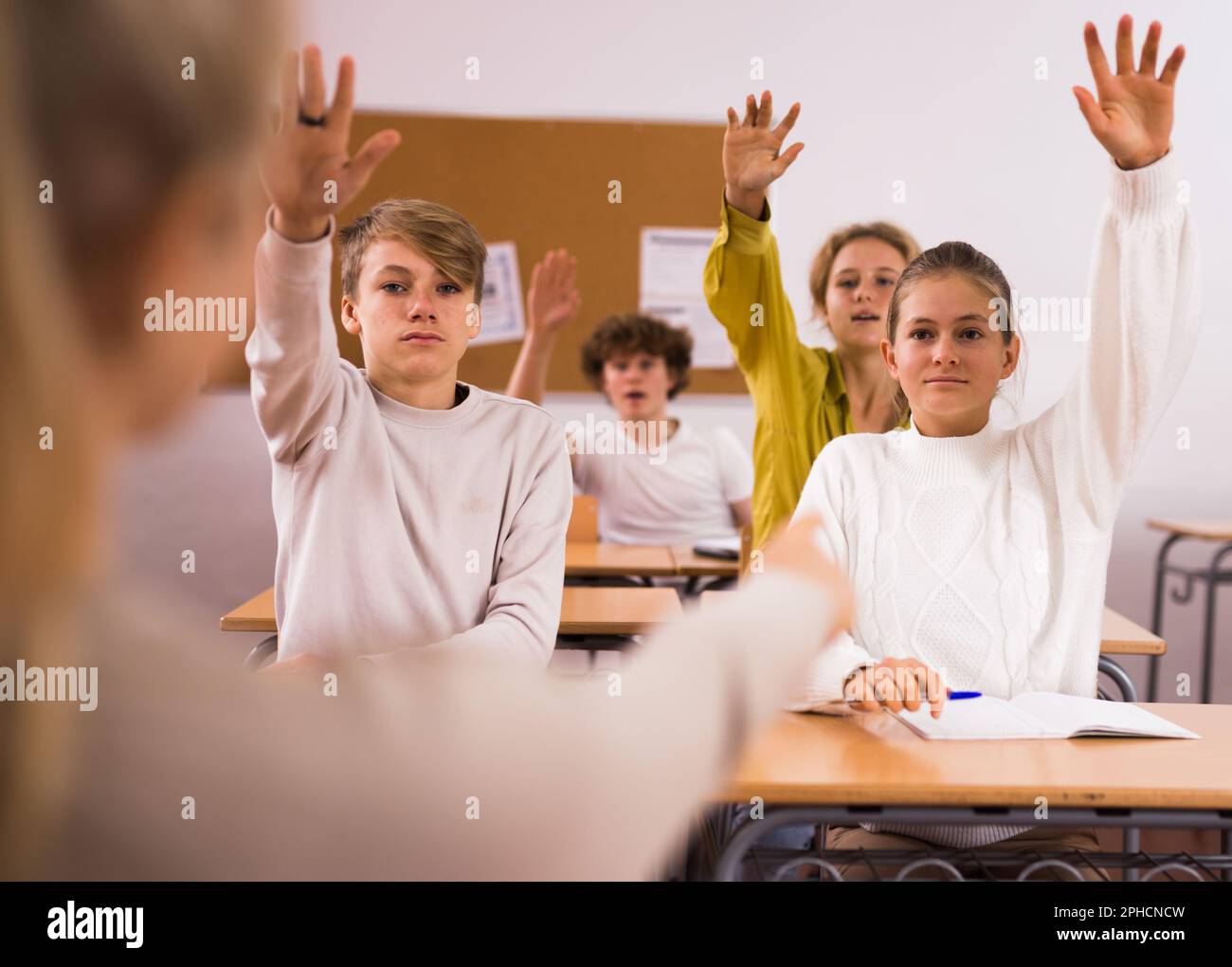 Pupils raising hands during lesson Stock Photo - Alamy