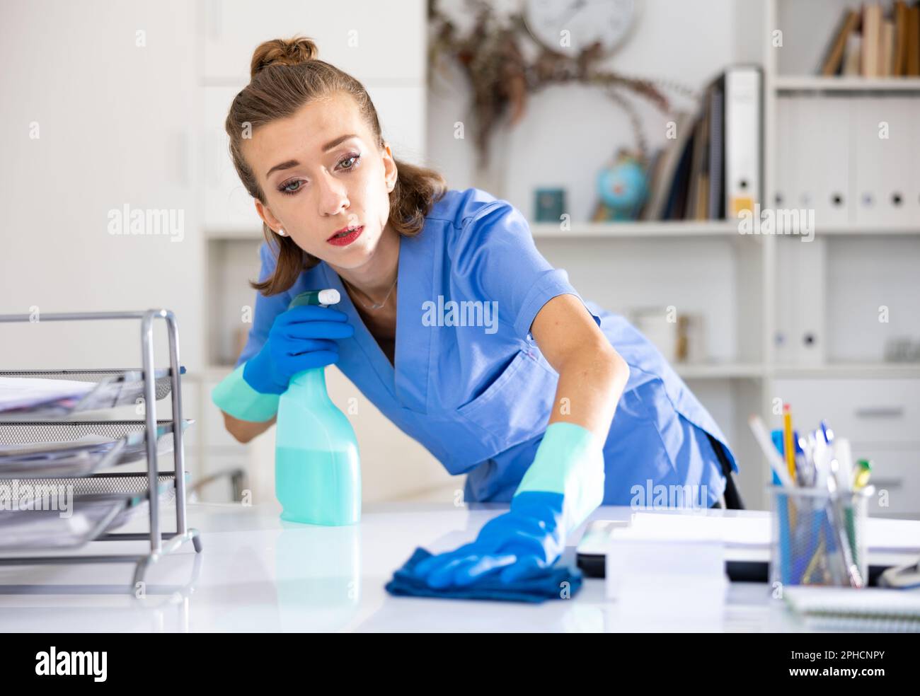 Cleaning lady in uniform wipes dust from table in office Stock Photo ...