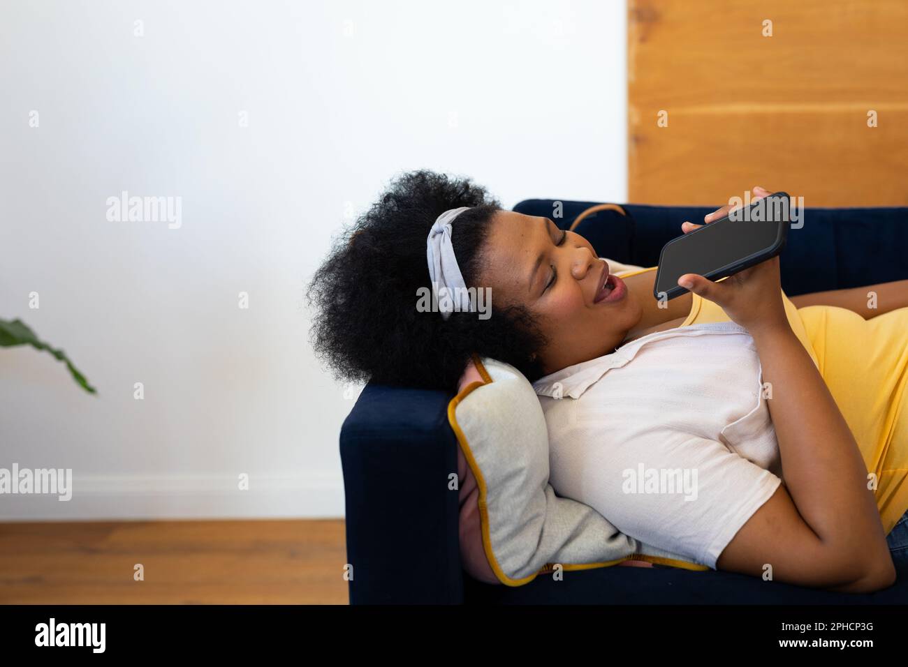 Happy plus size african american woman lying on sofa and talking on ...