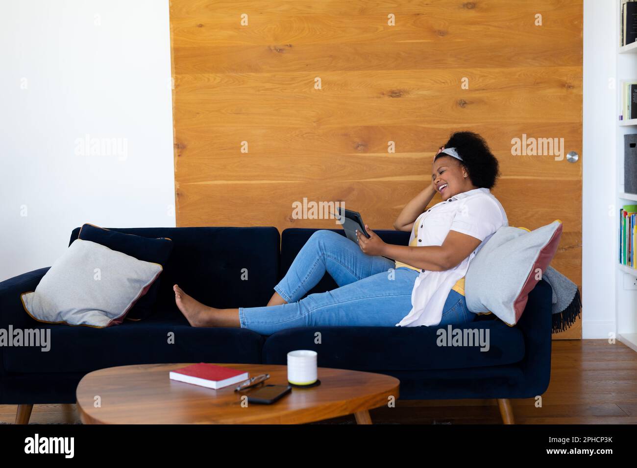 Happy Plus Size African American Woman Relaxing On Sofa Using Tablet