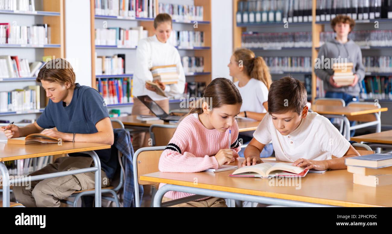 School friends spending time together in library, reading books Stock ...