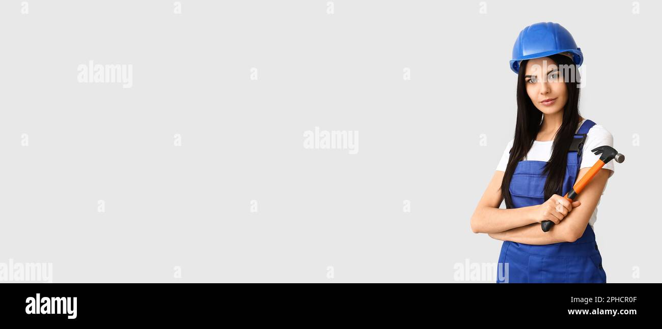 Beautiful female worker with hammer on light background with space for ...