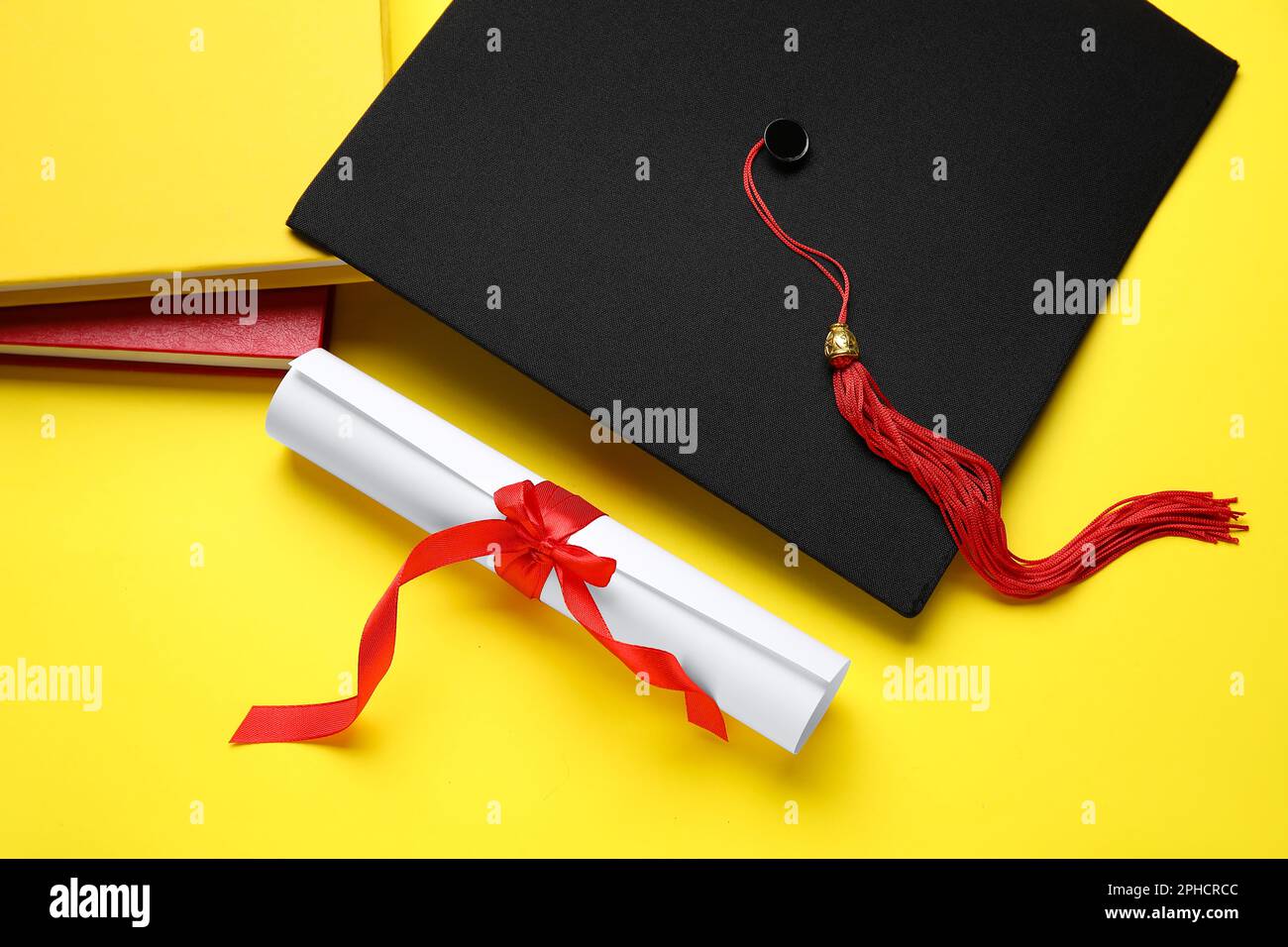 Diploma with red ribbon, graduation hat and books on yellow background ...