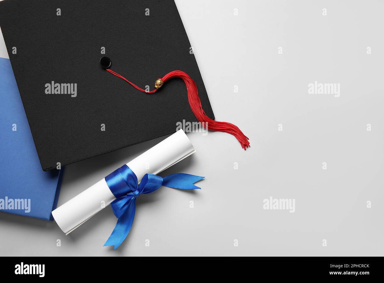 Diploma with blue ribbon, graduation hat and book on white background ...
