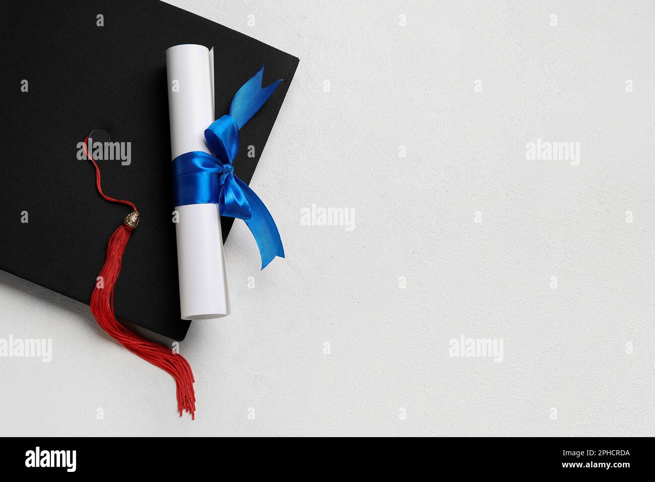 Diploma with blue ribbon and graduation hat on white table Stock Photo ...