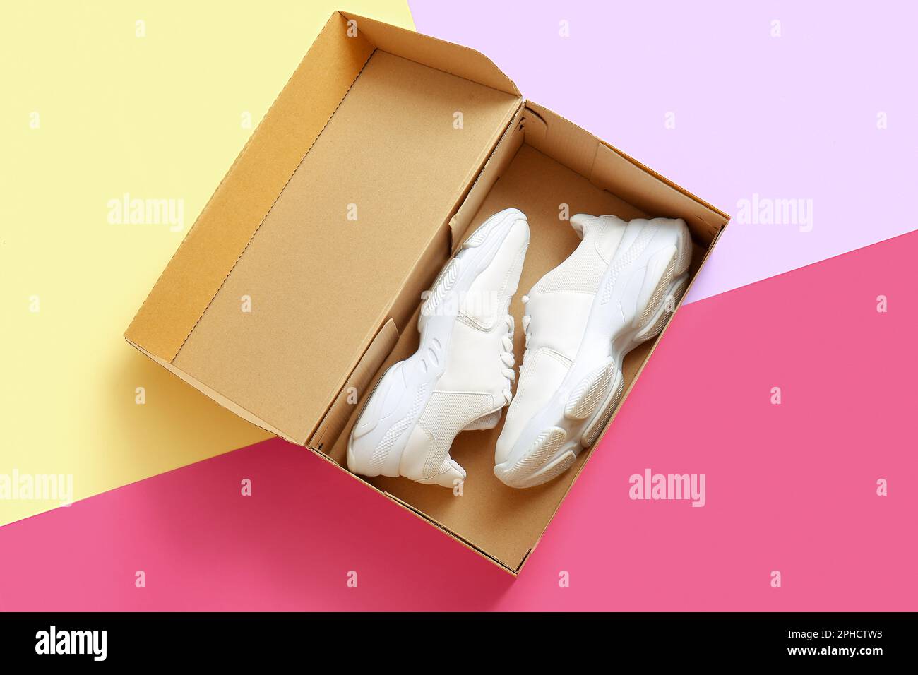 Cardboard box with sports shoes on color background Stock Photo - Alamy