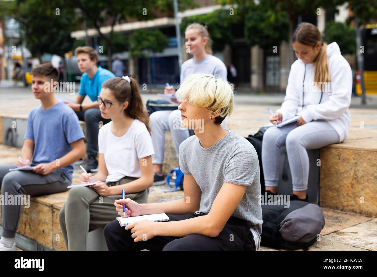 Students record lecture while sitting on a stone street parapet Stock ...