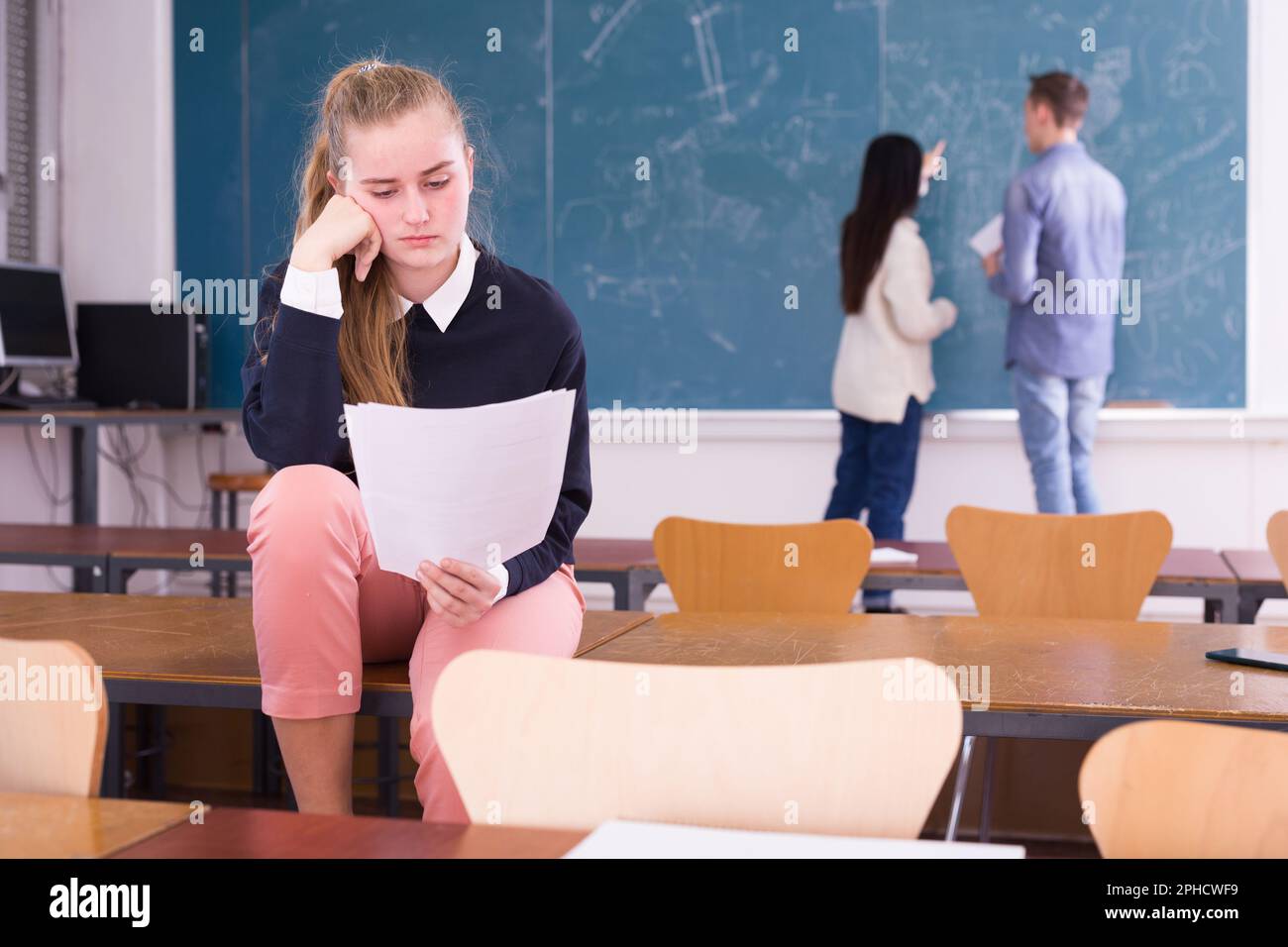 Frustrated girl student sitting in classroom with paper Stock Photo - Alamy