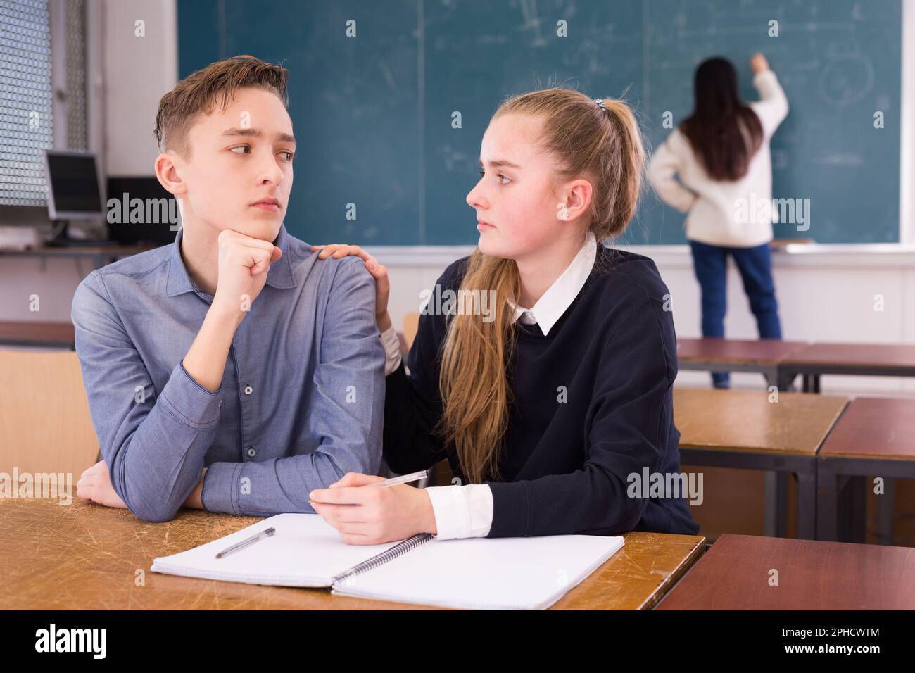 Thoughtful young students during writing notes in classroom Stock Photo ...