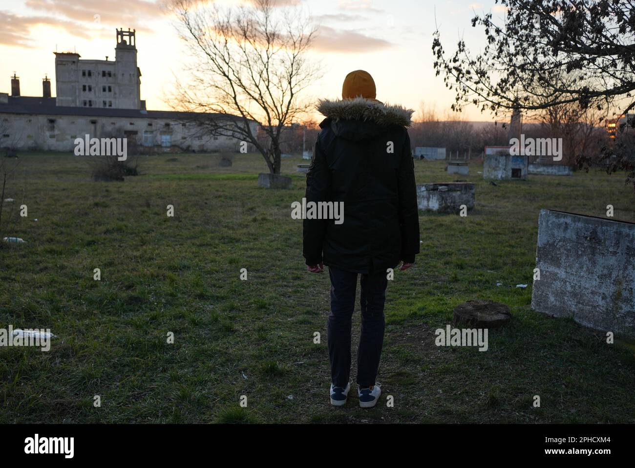 Tall guy standing looking at a scary old building alone in distance ...