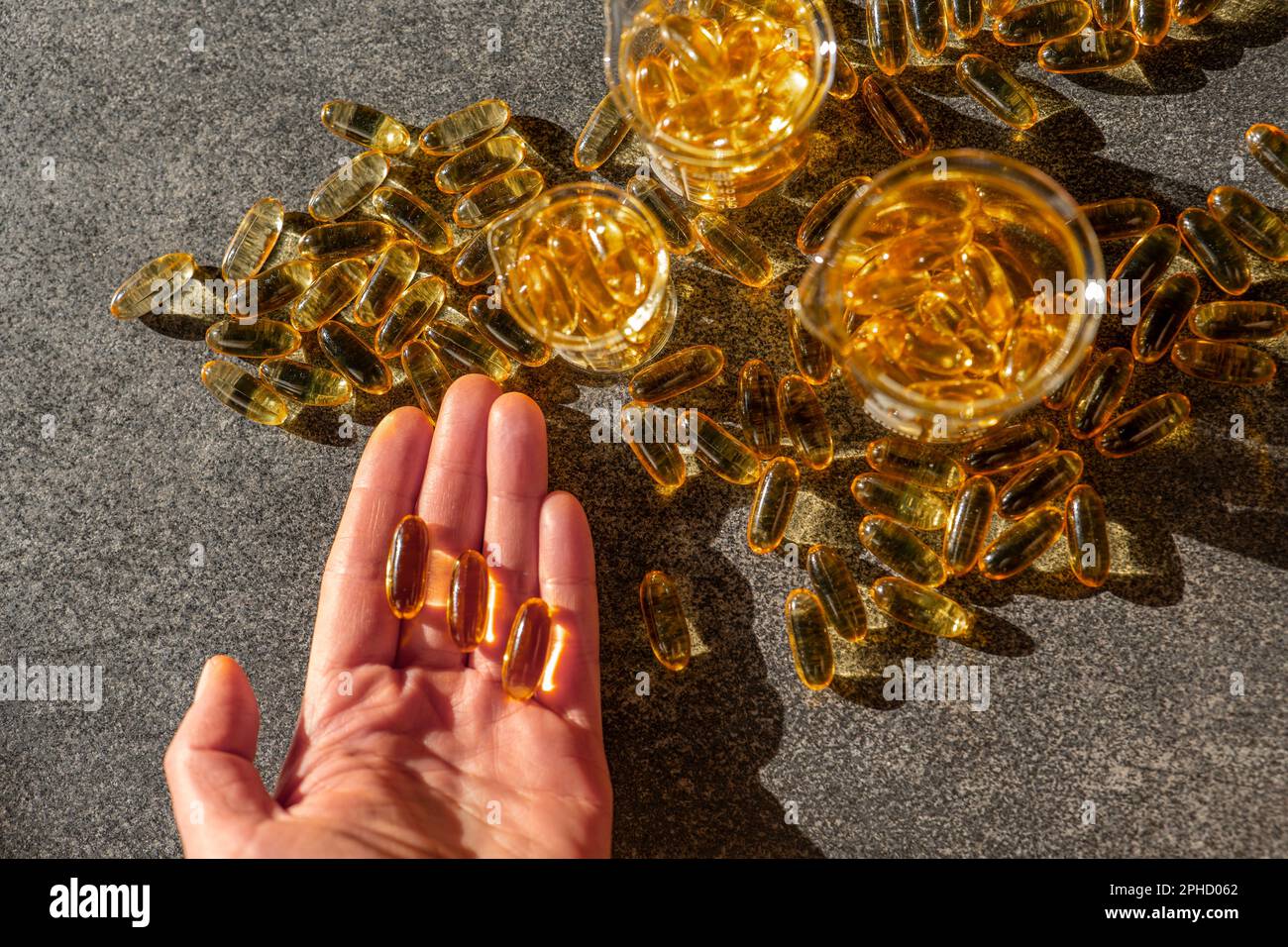 Fish oil capsules in hand on a slate background in hard light .omega ...
