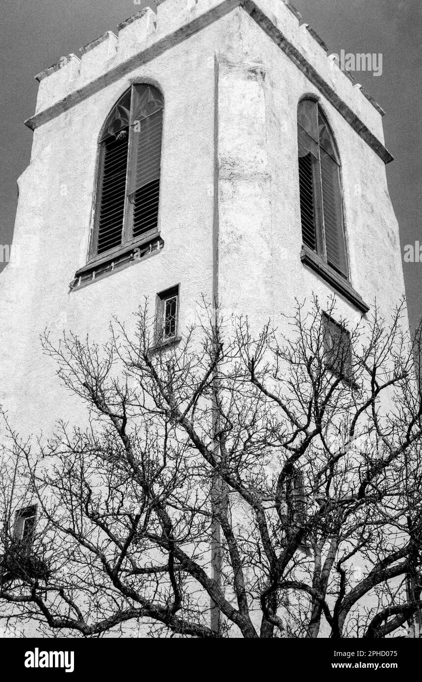 The tower of a weathered classic white stucco church with vintage ...