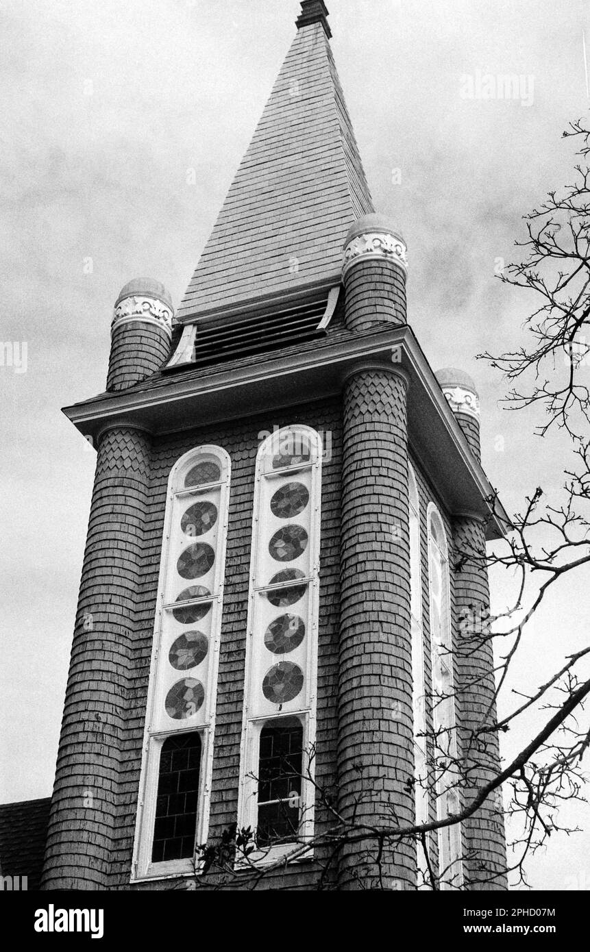 A classic church steeple with round stained glass windows surrounded in ...