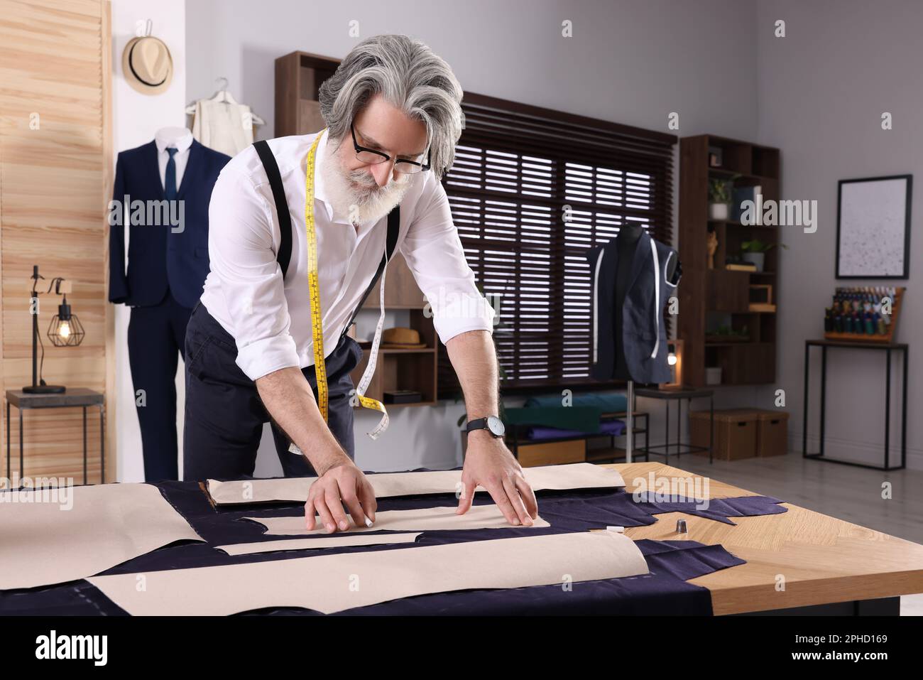 Professional tailor marking sewing pattern on fabric with chalk at ...