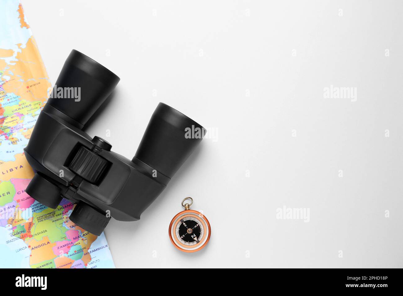 Modern binoculars, compass and world map on white background, flat lay. space for text Stock ...