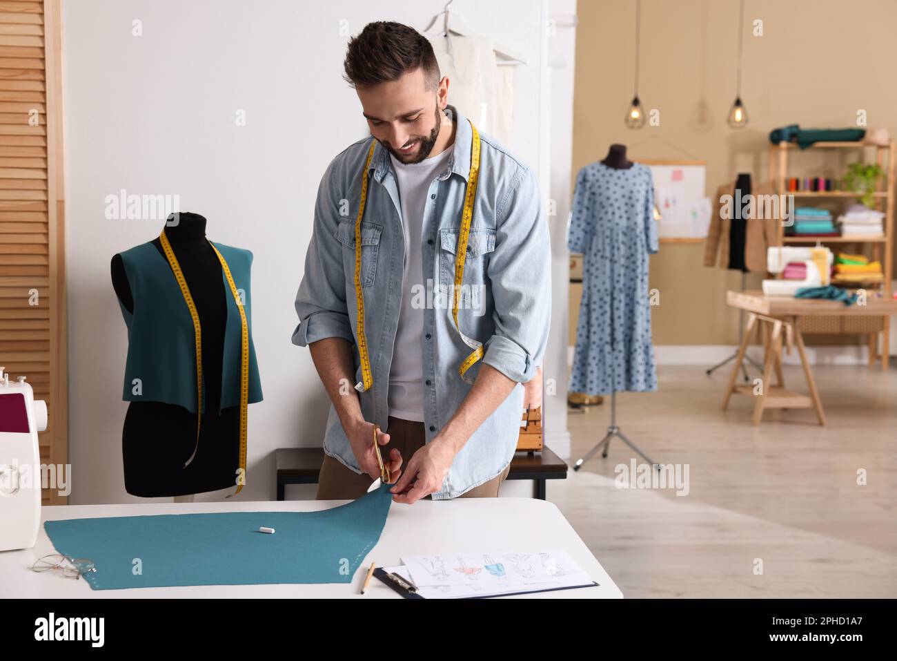 Dressmaker cutting fabric at table in workshop Stock Photo - Alamy
