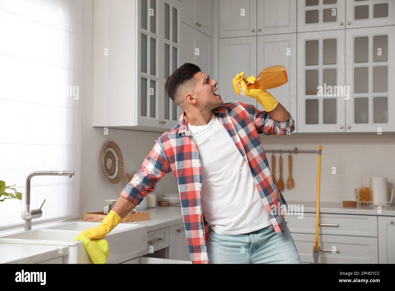 Man with spray bottle and rag singing while cleaning at home Stock ...