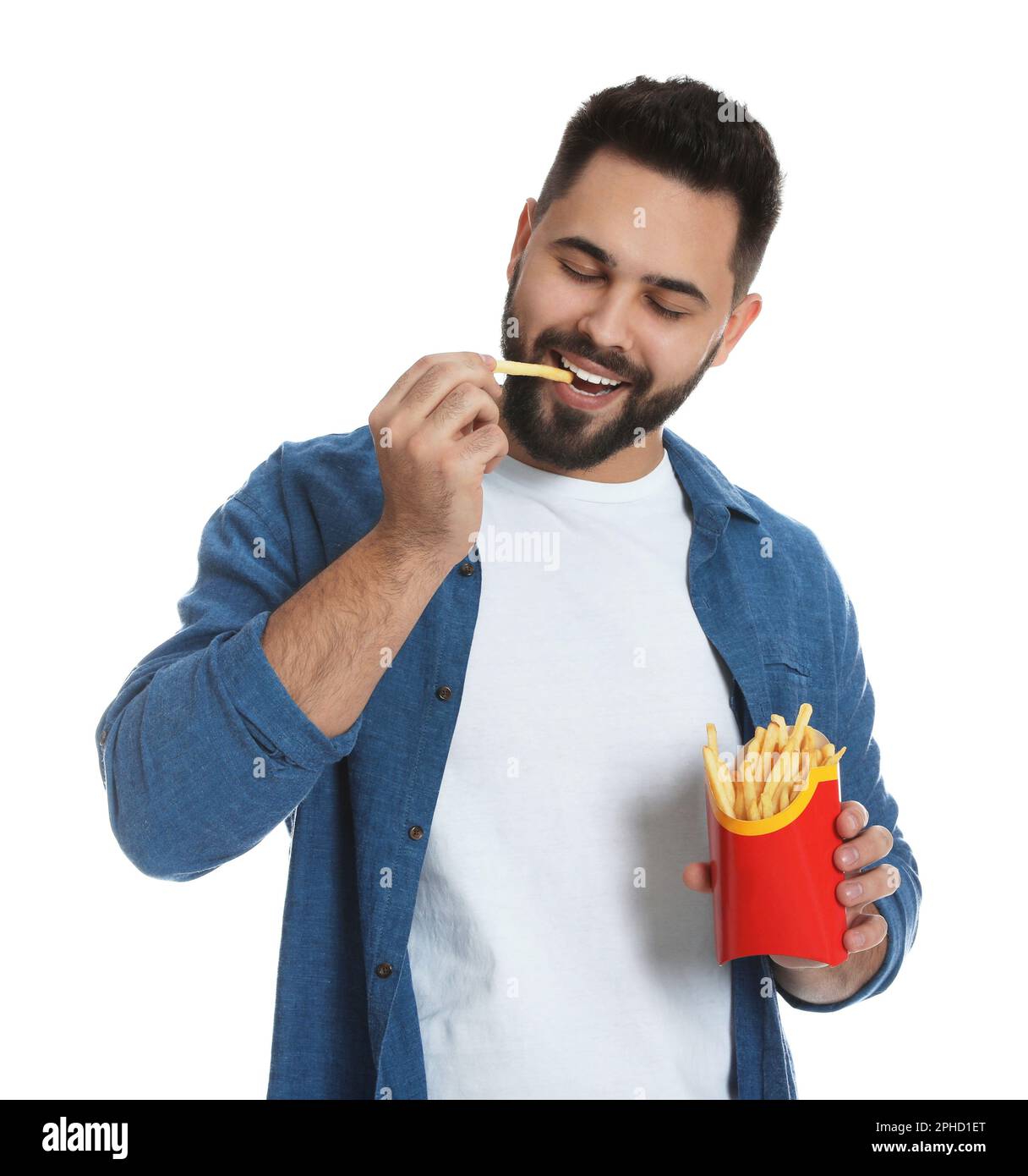 Young man eating French fries on white background Stock Photo - Alamy