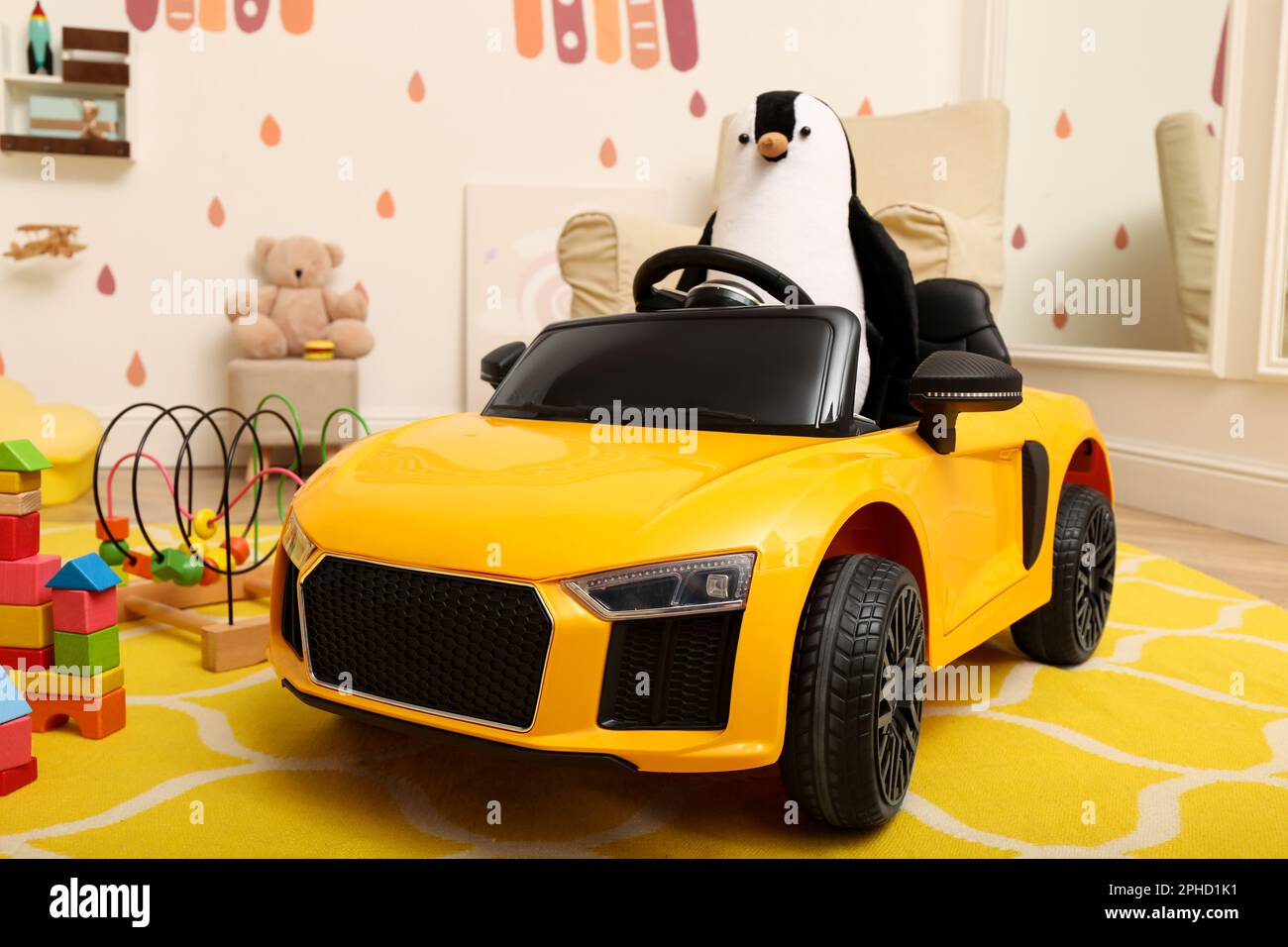 Child's electric car with toy penguin in playroom Stock Photo - Alamy