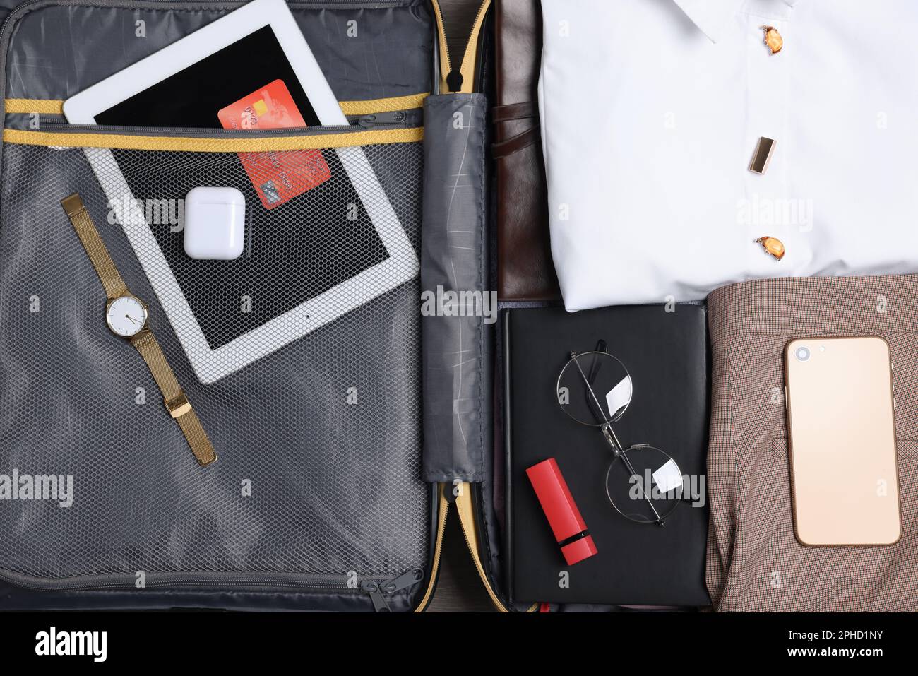 Open suitcase with folded clothes and accessories, closeup. Packing for ...