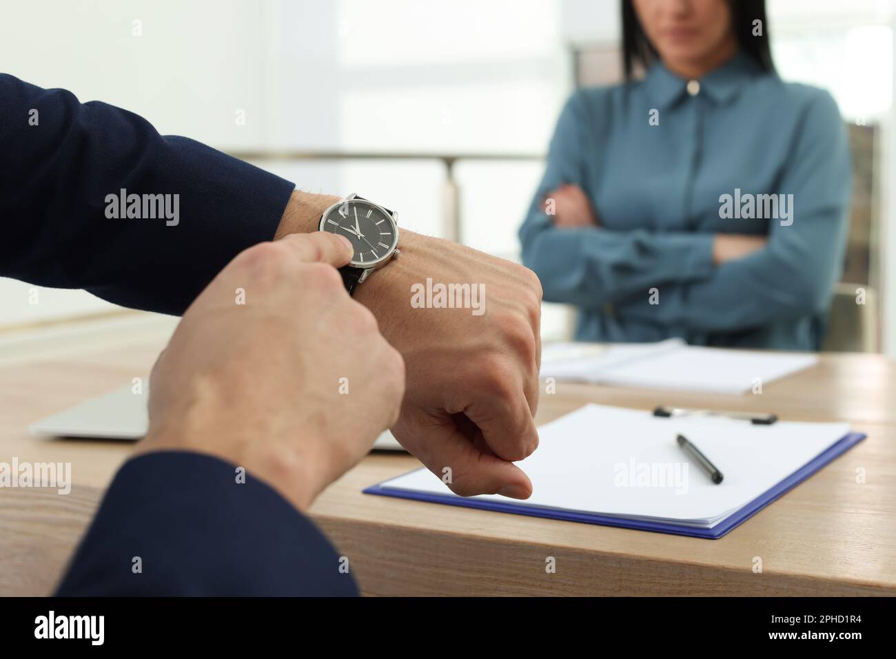 Businessman pointing on wrist watch while scolding employee for being ...