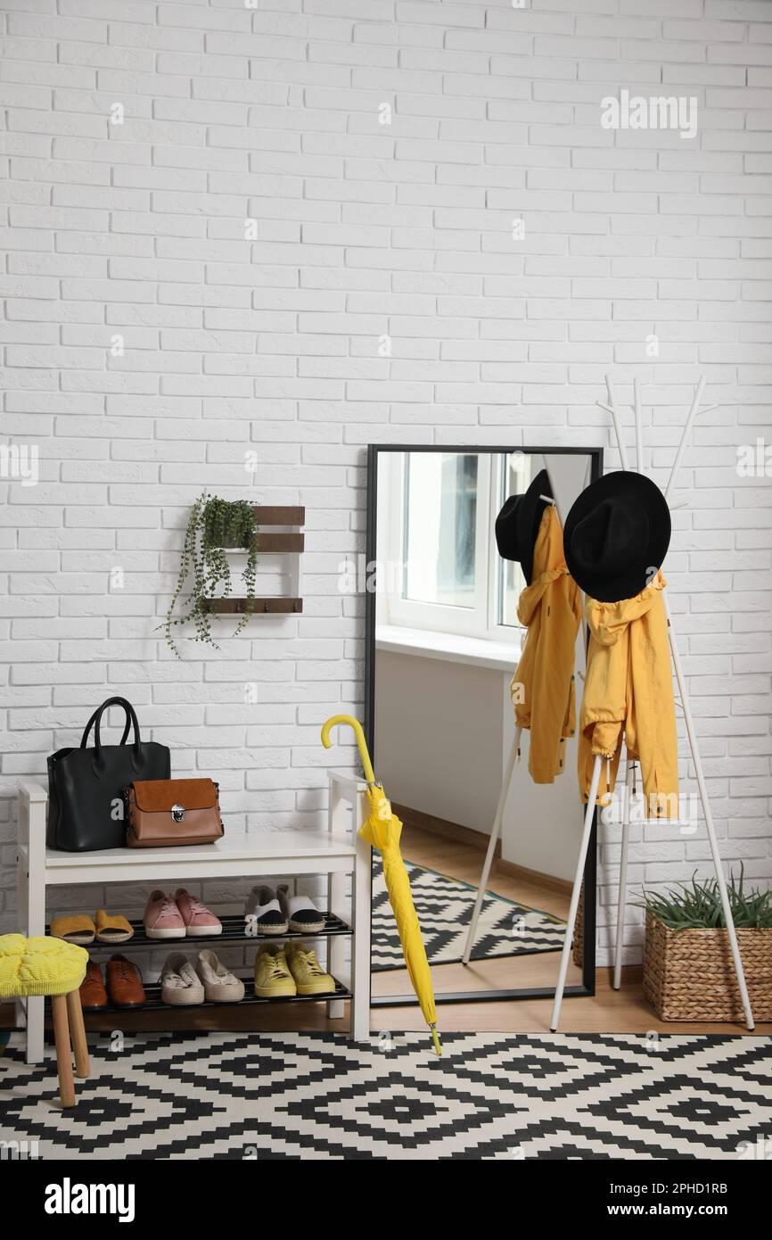 Stylish hallway interior with coat rack, shoe storage bench and mirror ...